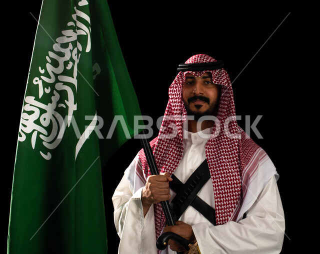 Portrait of a Saudi Arabian Gulf man raising the Saudi flag, wearing ...
