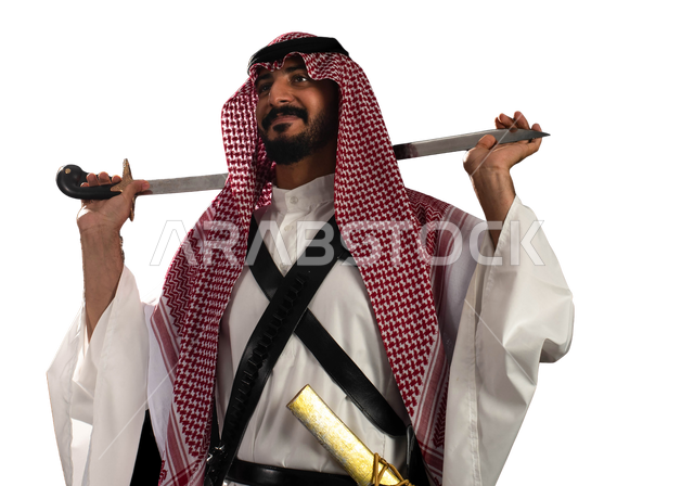 A Saudi Arabian Gulf man, holding a long sword in his hand, wears the ...