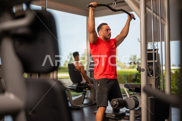 A Saudi Arabian Gulf man wearing sports clothes in the gym, doing ...