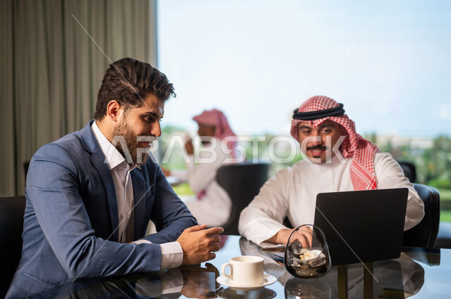 A Saudi Arabian Gulf businessman with an Arab businessman wearing a ...