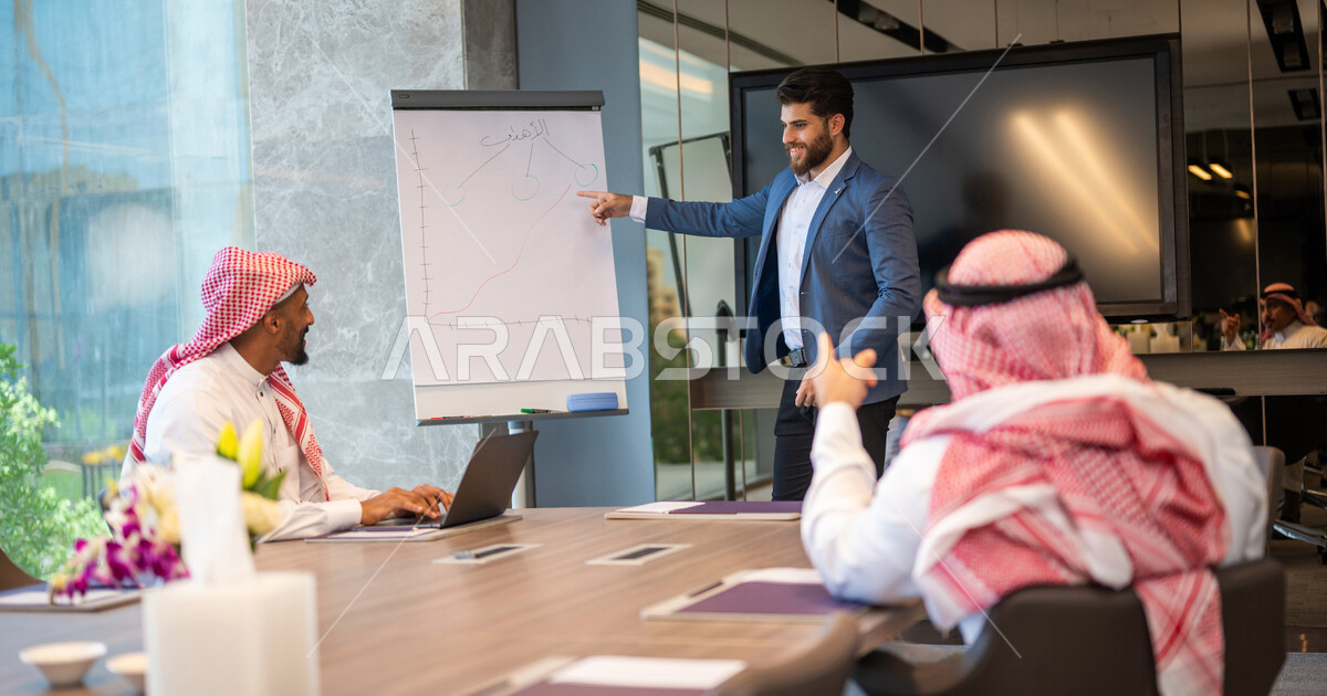 فريق عمل سعودي ورجل بالبدلة الرسمية في غرفة الإجتماعات داخل مقر الشركة ...