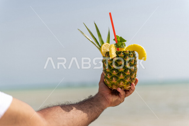Close-up of a Saudi Arabian Gulf man holding a piece of pineapple in ...