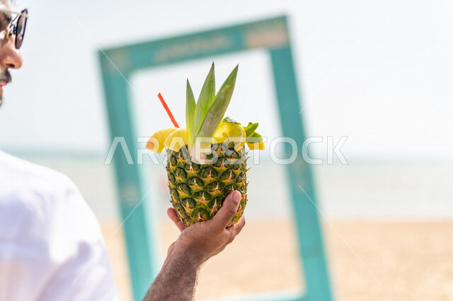 A close-up of a Saudi Arabian Gulf man holding a piece of pineapple in ...