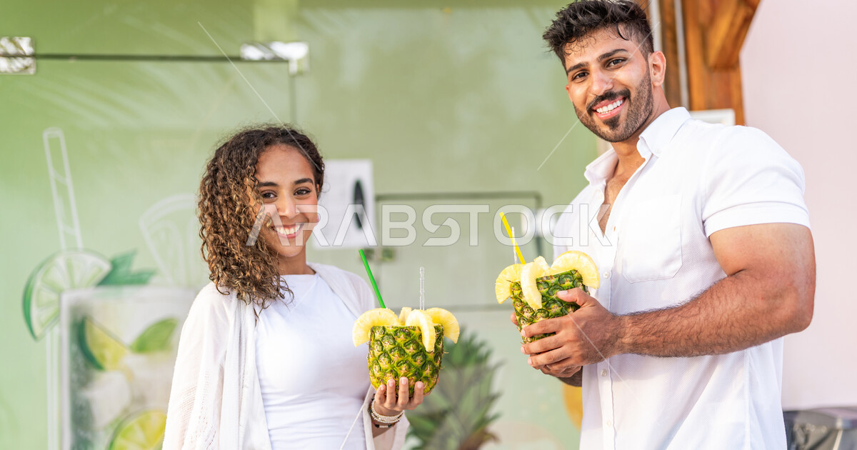 A Saudi Arabian Gulf couple holding a pineapple and looking towards the ...