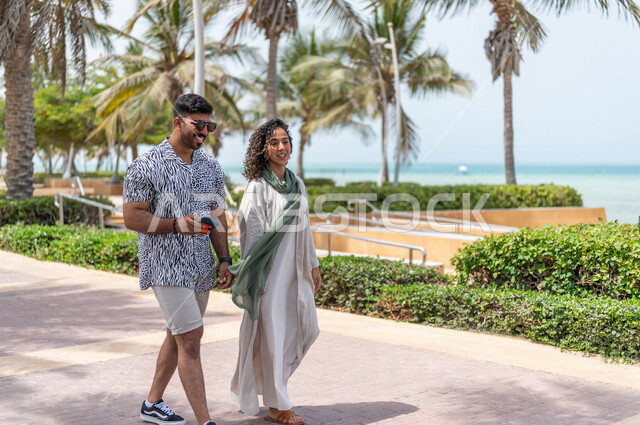 A Saudi Arabian Gulf man and woman walking in Jeddah Corniche promenade ...