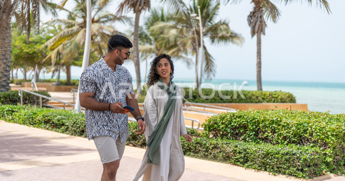 A Saudi Arabian Gulf man and woman walking in Jeddah Corniche promenade ...
