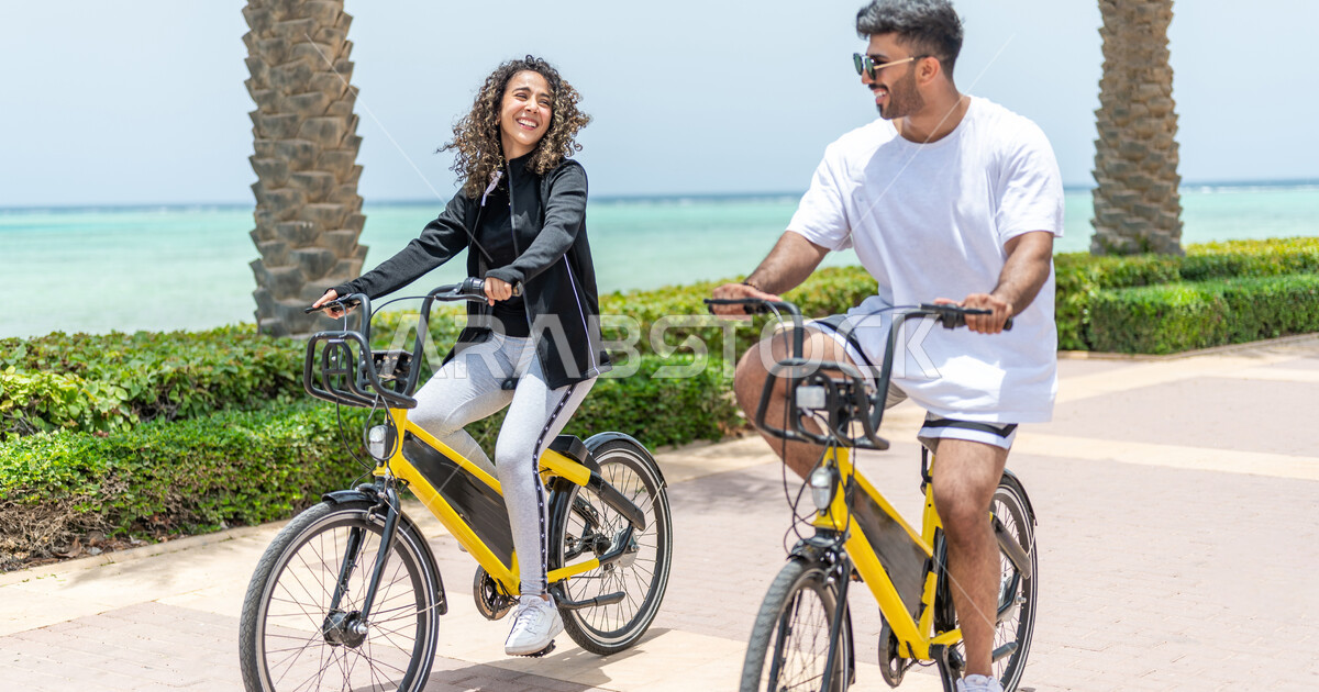 A Saudi Arabian Gulf man and woman riding bicycles on the Jeddah ...