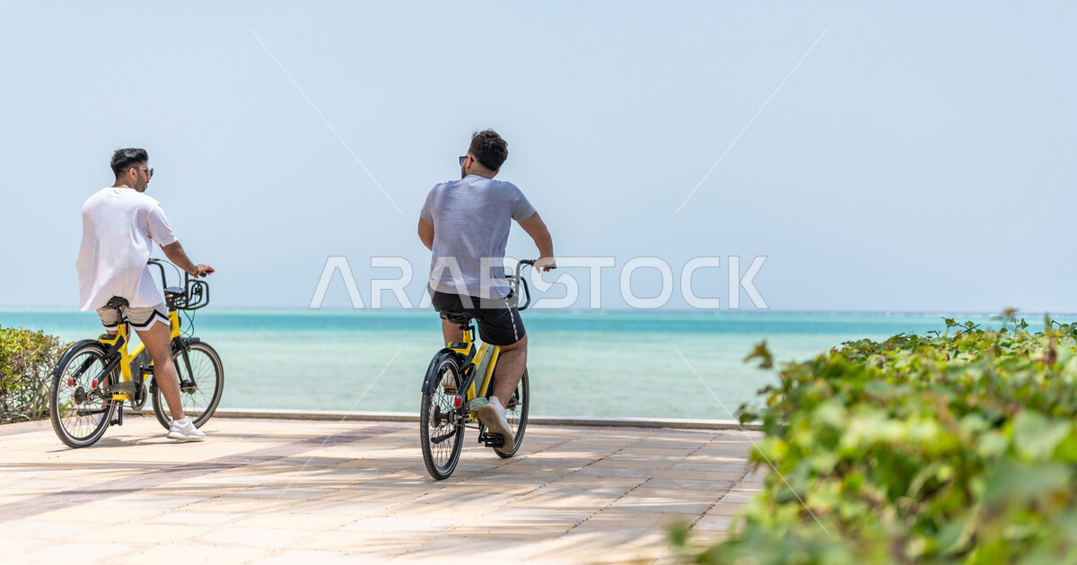 Two Saudi Arabian Gulf youths riding a bicycle in the Jeddah Corniche ...