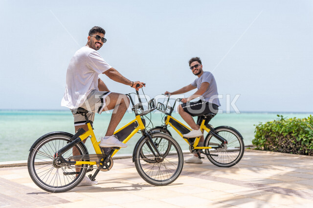 Two Saudi Arabian Gulf youths riding a bicycle in the Jeddah Corniche ...