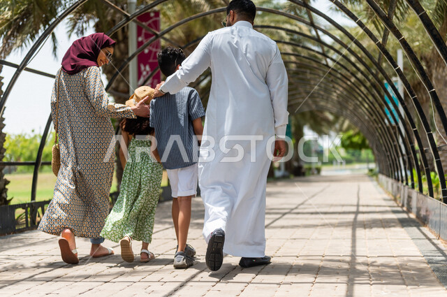 A corner from the back of a Saudi Arabian Gulf family walking on the ...