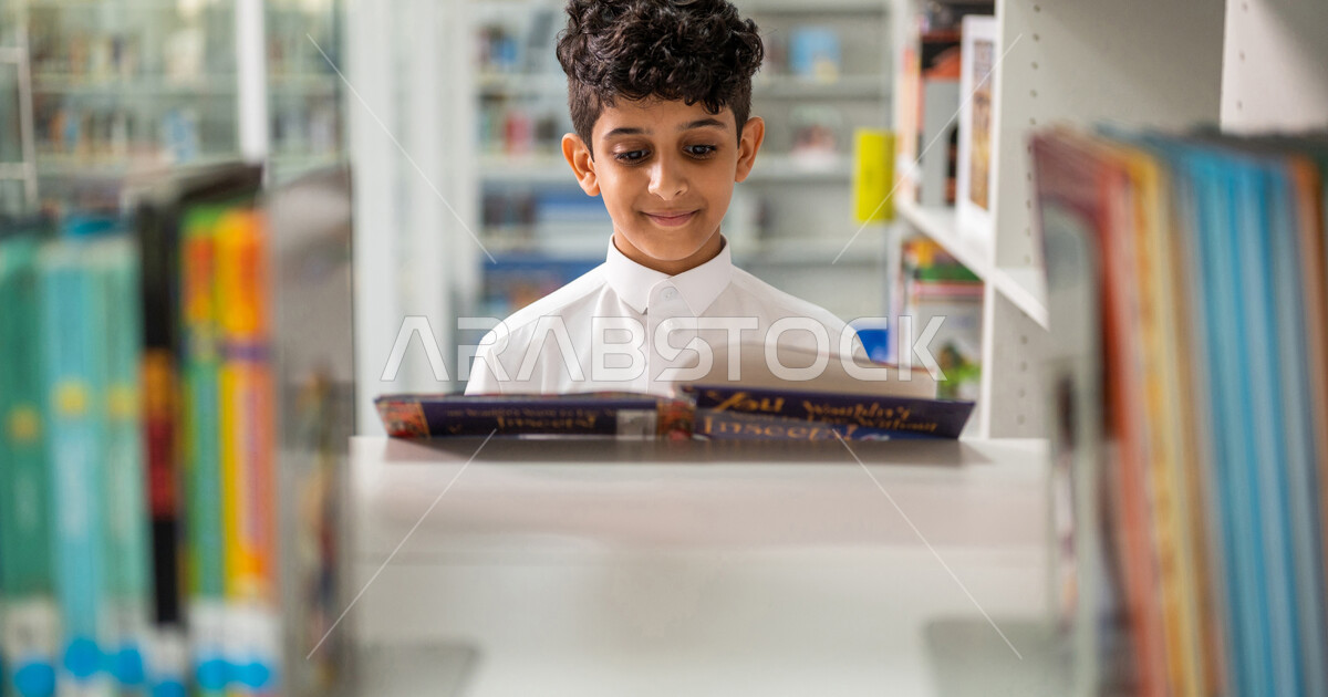 A Saudi Arabian Gulf student reading a book from the school library ...