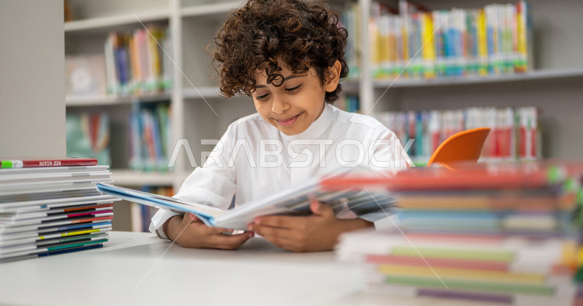 A Saudi Arabian Gulf student reading a book from the school library ...