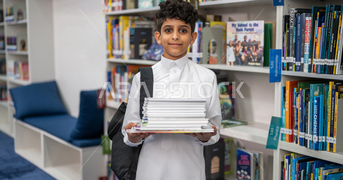 A Saudi Arabian Gulf student carrying a set of books inside the school ...