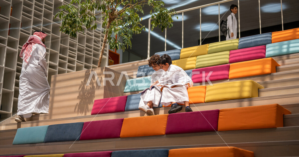 Two Saudi Arabian Gulf students sitting on the stairs in the school ...