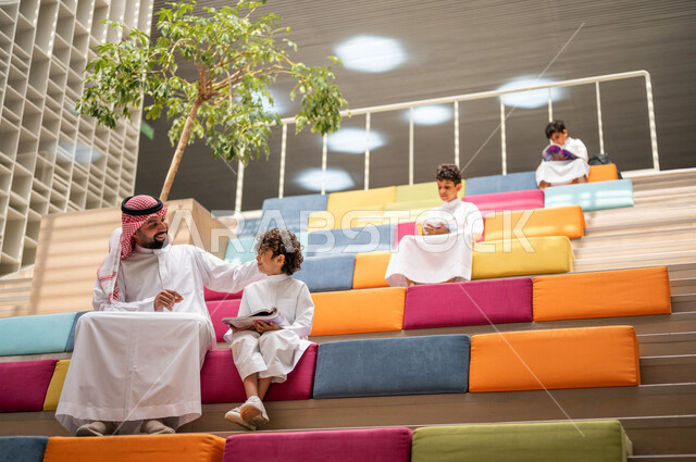 A Saudi Arabian Gulf professor with a group of students sitting on the ...