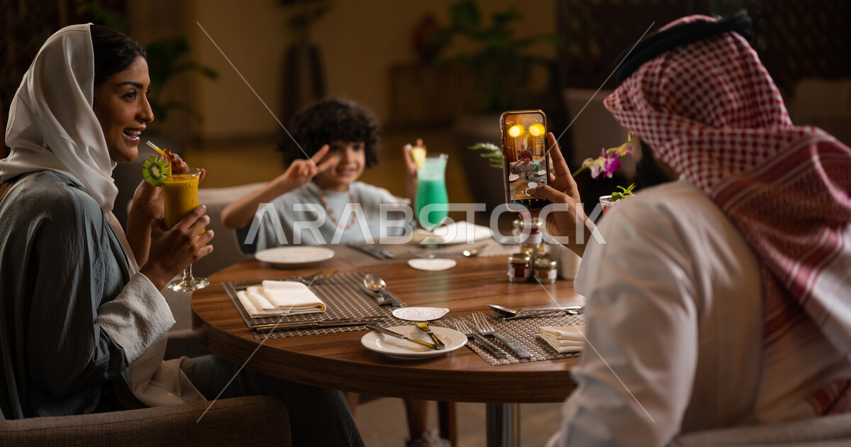A Saudi Arabian Gulf family sitting in the restaurant, eating natural ...