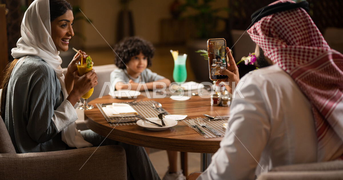A Saudi Arabian Gulf family sitting in the restaurant, eating natural ...