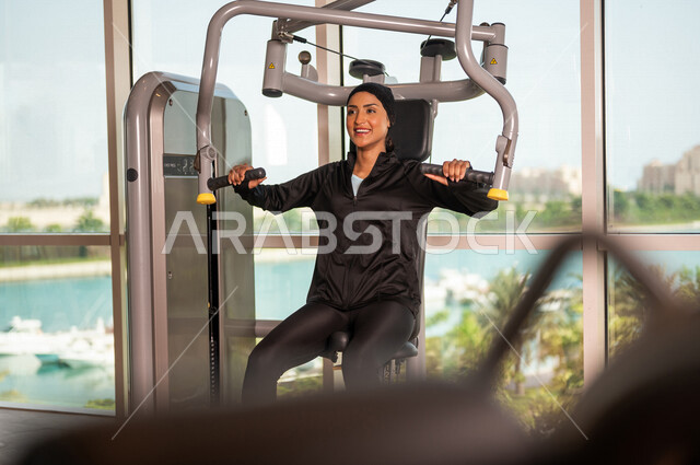 A Saudi Arabian Gulf woman wears sports clothes and exercises, uses ...
