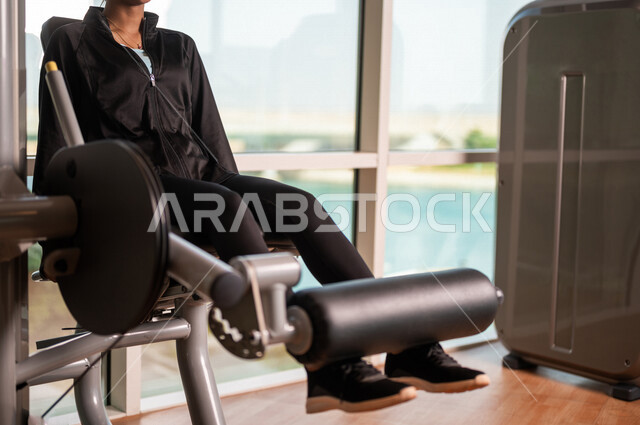 A Saudi Arabian Gulf woman wears sports clothes and exercises, uses ...
