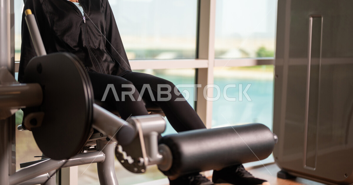 A Saudi Arabian Gulf woman wears sports clothes and exercises, uses ...