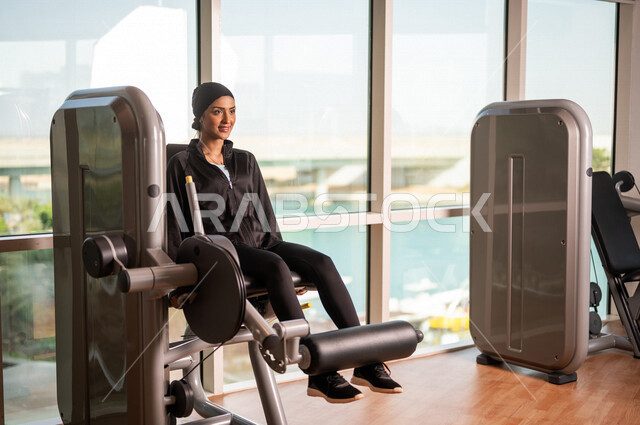 A Saudi Arabian Gulf woman wears sports clothes and exercises, uses ...