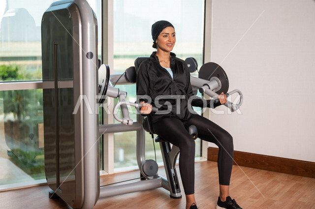A Saudi Arabian Gulf woman wears sports clothes and exercises, uses ...