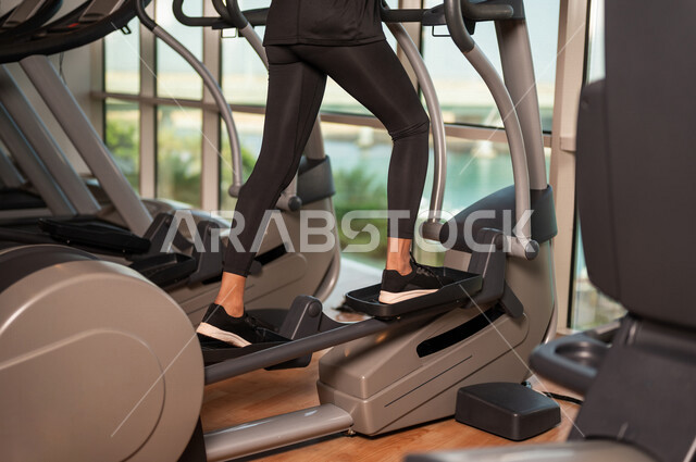 A Saudi Arabian Gulf woman wears sports clothes and exercises, uses ...