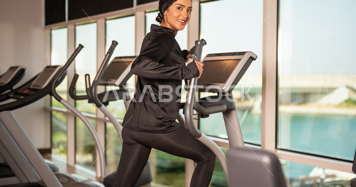 A Saudi Arabian Gulf woman wears sports clothes and exercises, uses ...