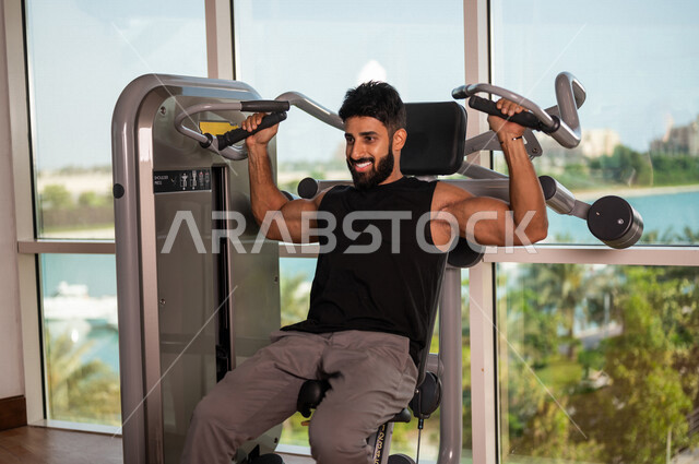 A Saudi Arabian Gulf man wears sports clothes and exercises, uses ...