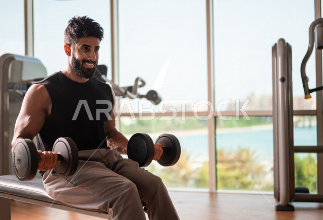 A Saudi Arabian Gulf man wears sports clothes and exercises, uses ...