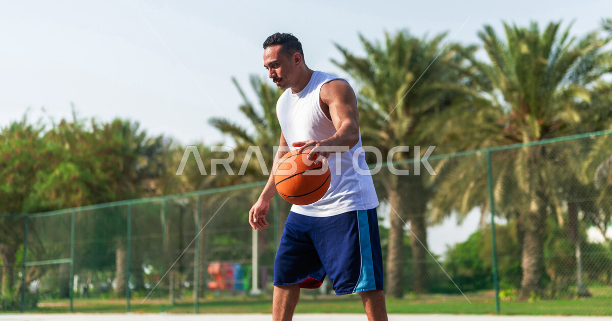 A Saudi Arabian Gulf youth playing basketball, practicing basketball in ...