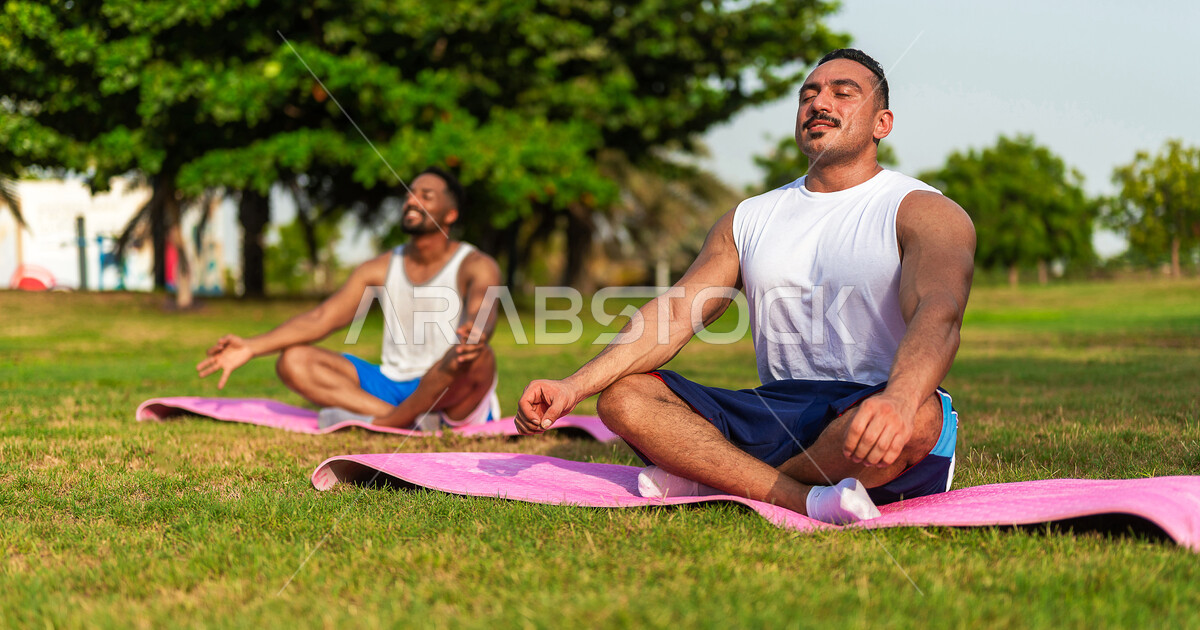 Two Saudi Arabian Gulf youths practicing meditative yoga, exercise ...