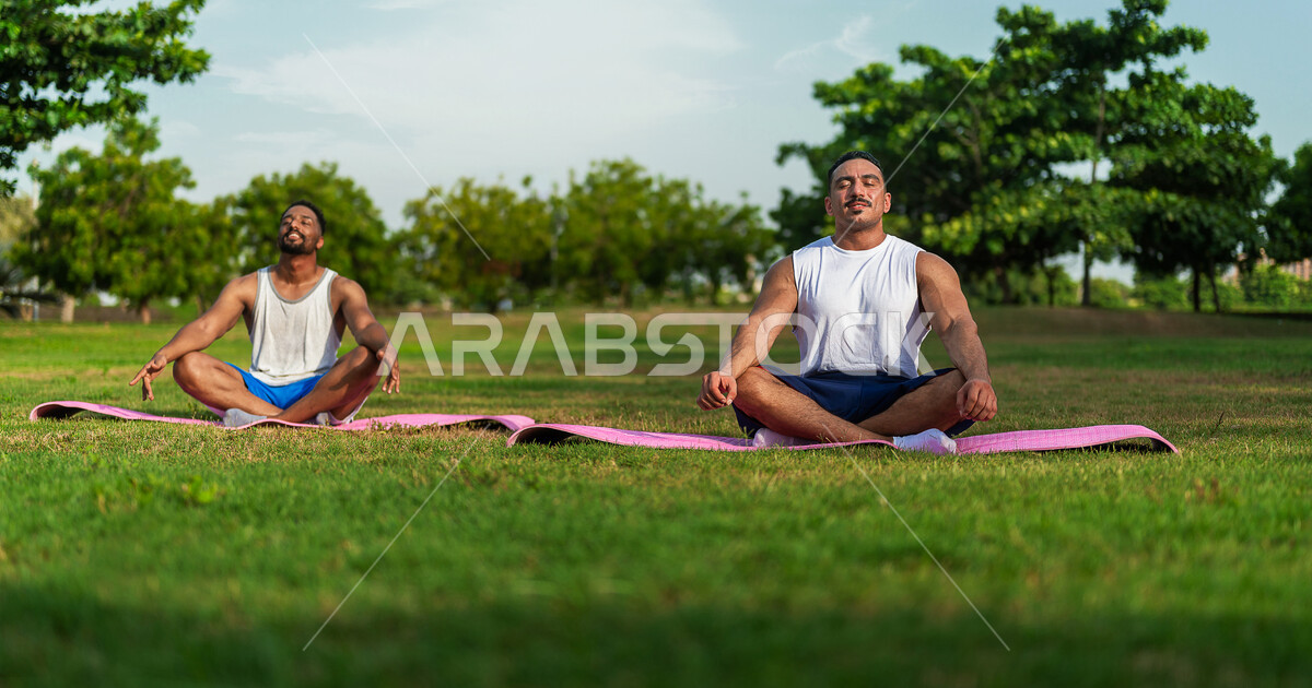 Two Saudi Arabian Gulf youths practicing meditative yoga, exercise ...