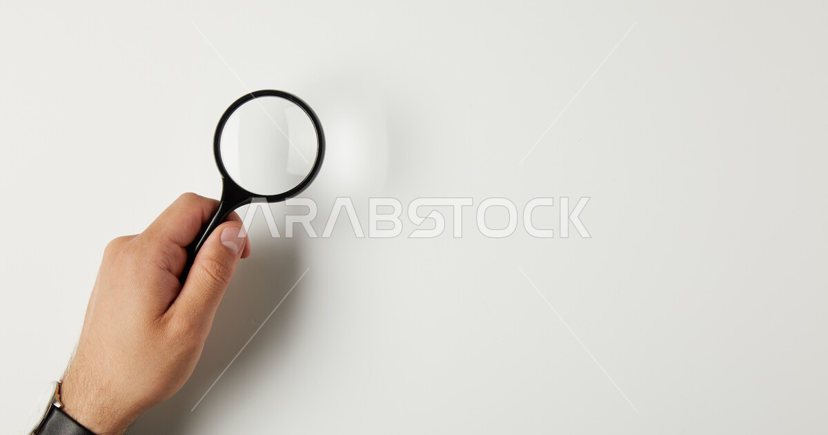 Close-up of a man's hand holding a magnifying glass, Using a magnifying ...