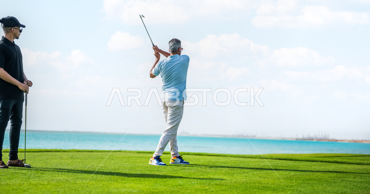 A picture of two Gulf Arab men wearing sports uniforms, playing golf on ...