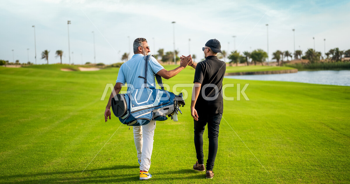 A picture of two Gulf Arab men wearing sports uniforms, playing golf on ...