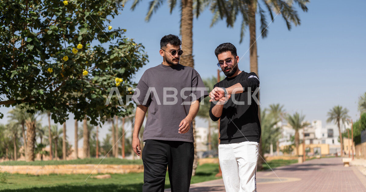 A close-up of two Saudi Arabian Gulf friends who meet in a public park ...