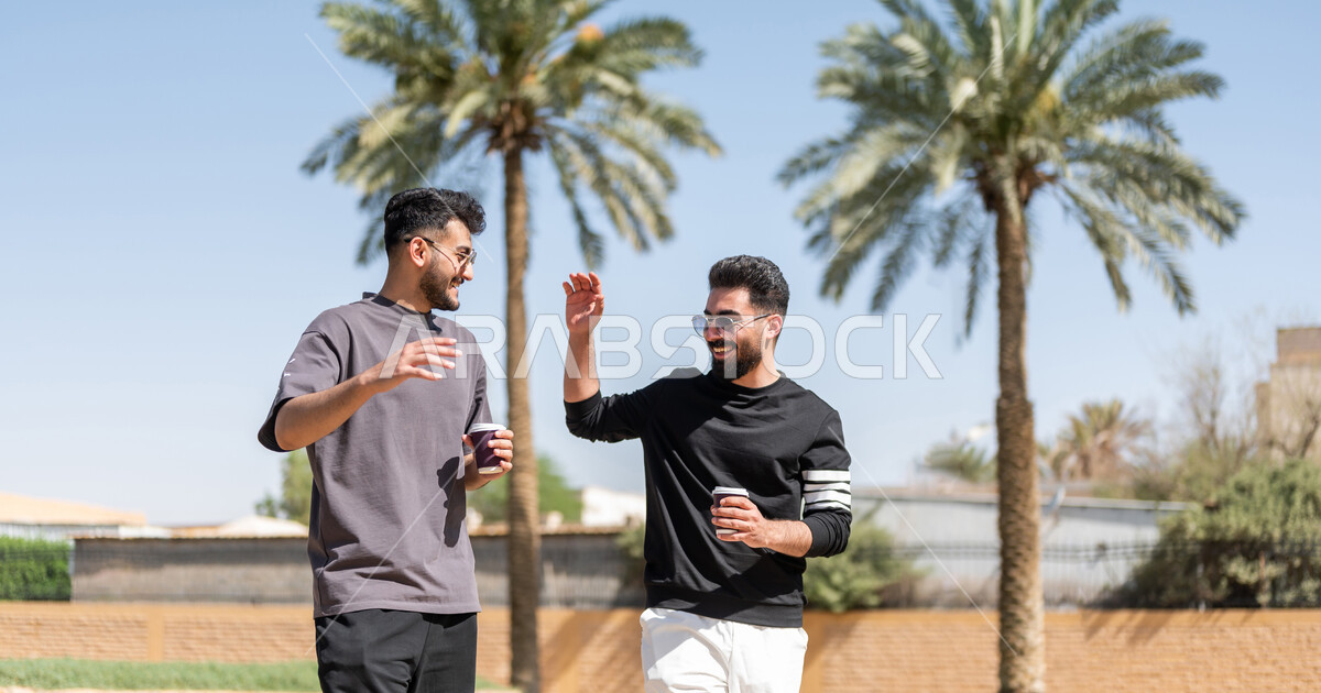 Two young Saudi Arabs from the Gulf meet in a public park and shake ...