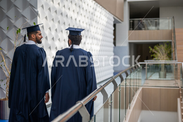 A picture from the back of two Saudi Arabian Gulf students wearing the abaya and graduation cap ...