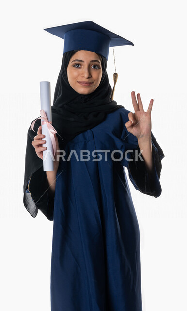 Portrait of a Saudi Arabian Gulf student wearing an abaya and graduation cap, holding a ...