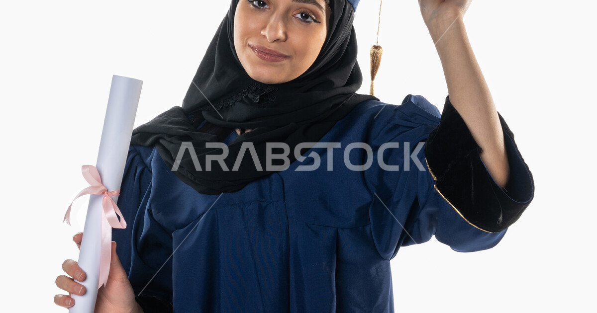 Portrait of a Saudi Arabian Gulf student wearing an abaya and graduation cap, holding a ...