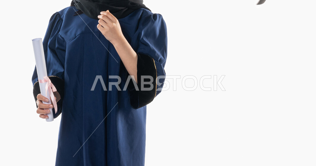 Portrait of a Saudi Arabian Gulf student wearing an abaya and graduation cap, holding a ...