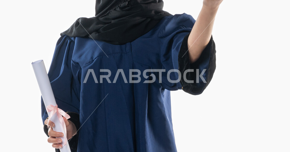Portrait of a Saudi Arabian Gulf student wearing an abaya and graduation cap, holding a ...