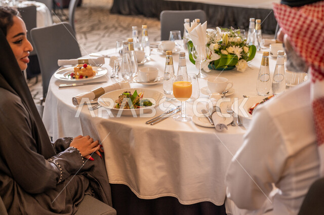 A close-up of a Saudi Arabian Gulf man and woman sitting at the table ...
