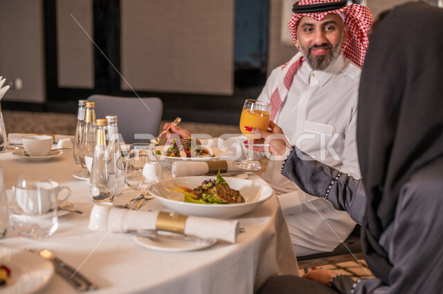 A close-up of a Saudi Arabian Gulf man and woman sitting at the table ...