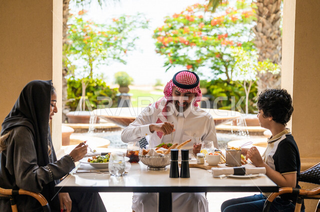 A Saudi Arabian Gulf family sitting in the restaurant, a dining table ...