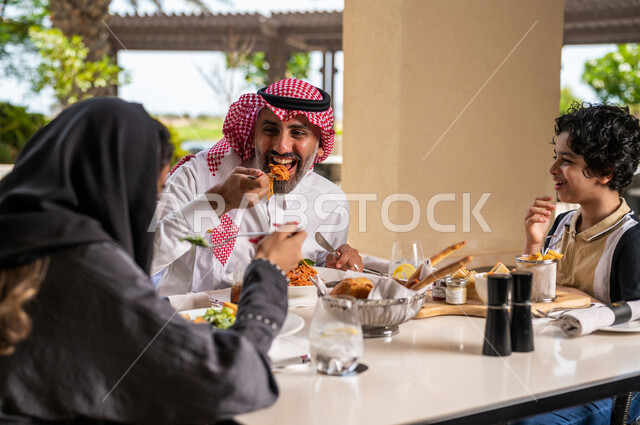 A Saudi Arabian Gulf family sitting in the restaurant, a dining table ...