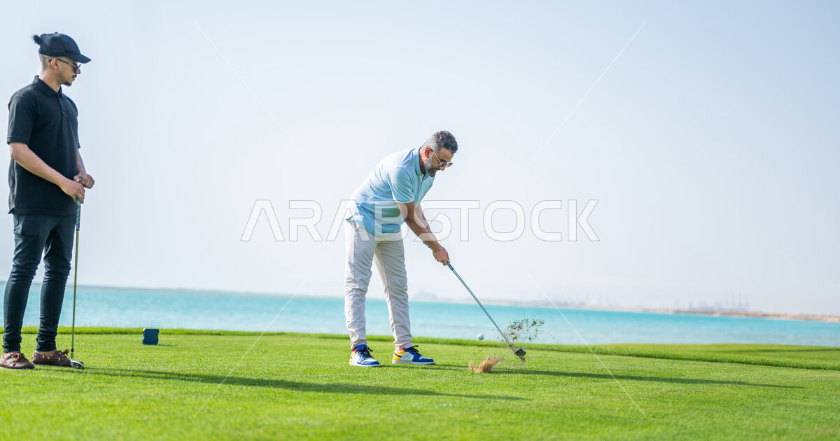 Two Saudi Arabian Gulf men wearing sports uniforms, playing golf on ...