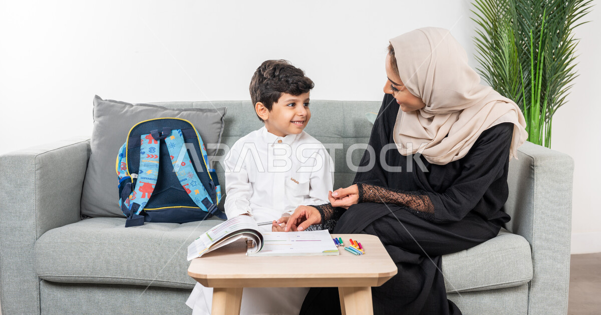 A veiled Saudi Gulf Arab mother helps her child learn at home, happy ...
