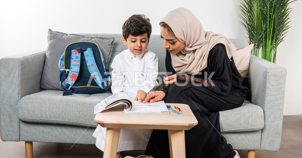 A veiled Saudi Gulf Arab mother helps her child learn at home, happy ...